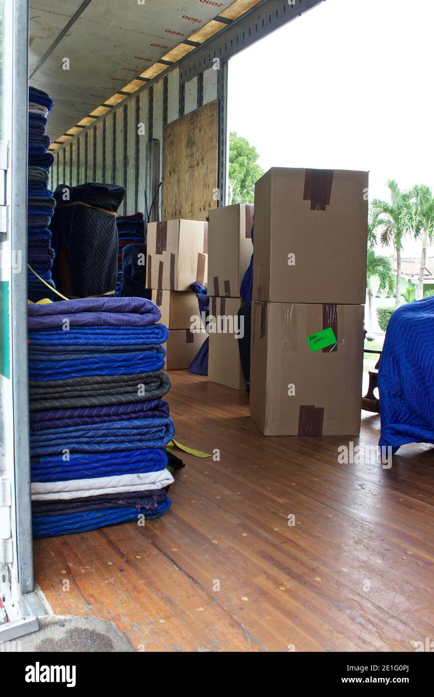 Moving van trailer with packed boxes by open door with bright labels or ...