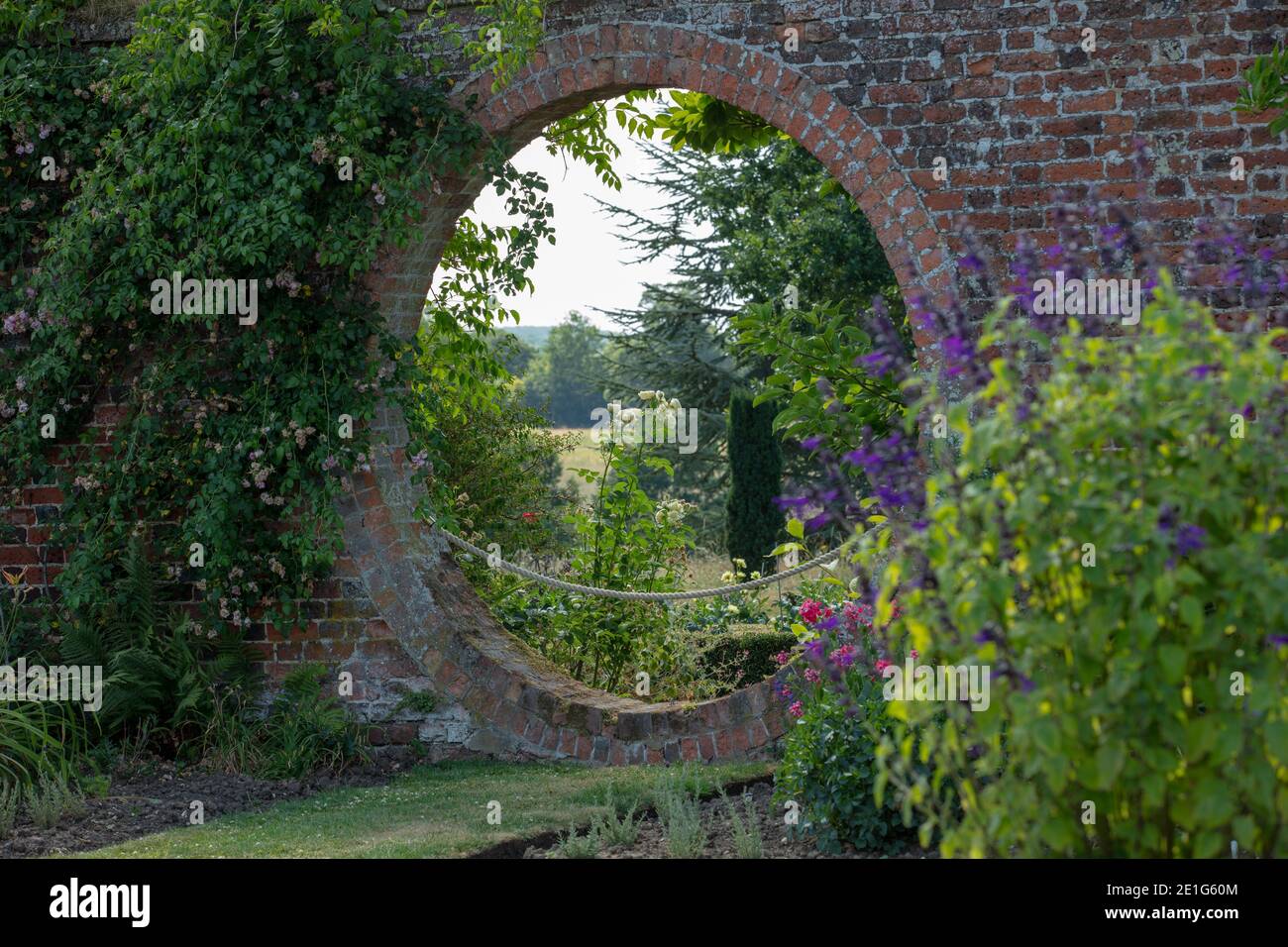 Garden wall with large circular window with a view onto the countryside ...