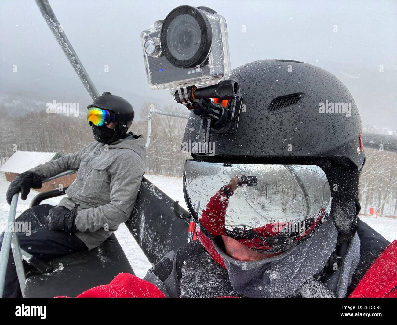 Skier wearing action camera on the top of his helmet on ski lift chair ...