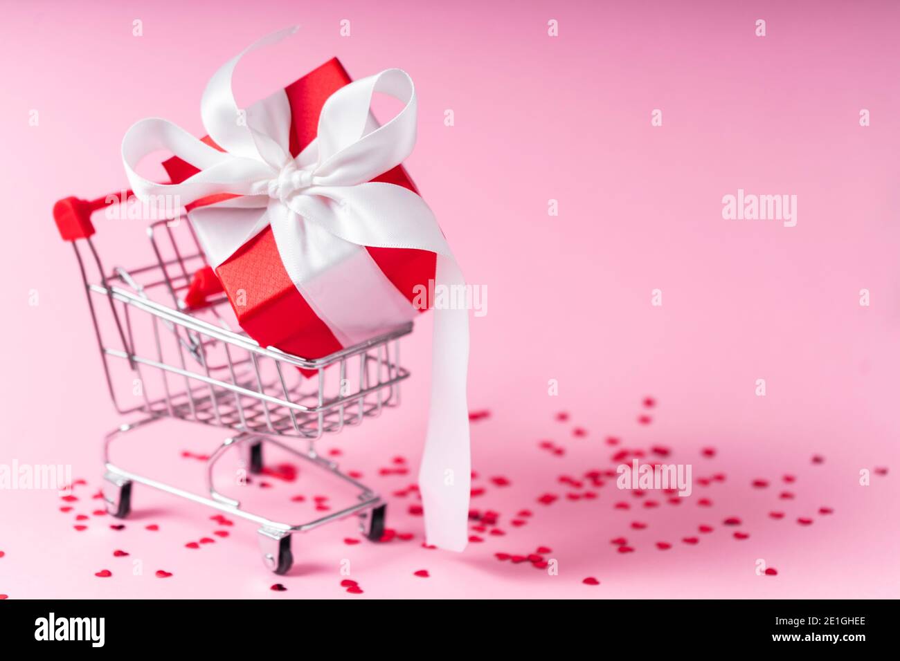 small red gift box with white ribbon and bow on pink background ...