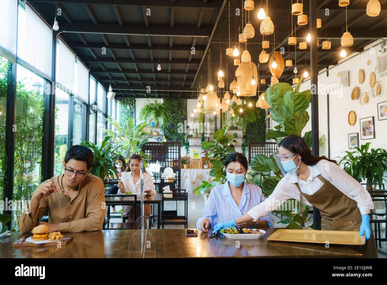 Asian woman waering mask and asian people eating food alone at table ...