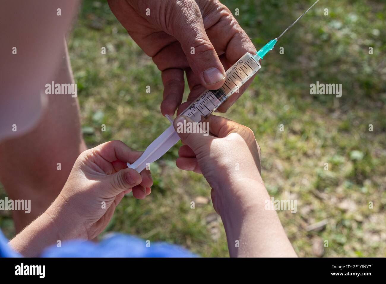 Child holds syringe with medicine in his hands. Elder explains to child ...