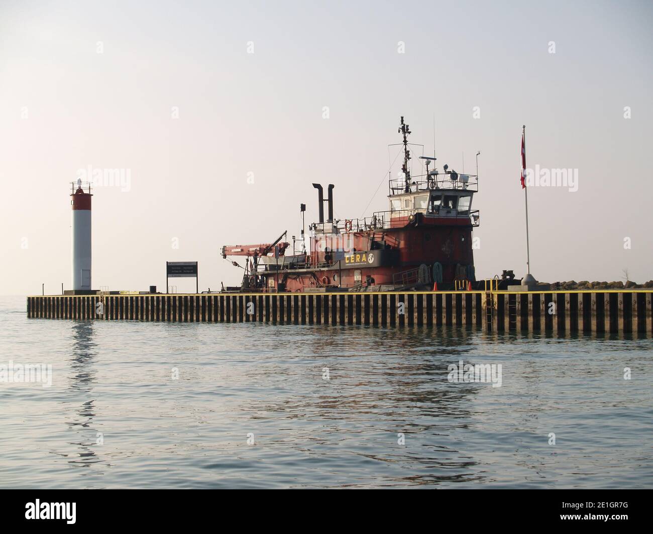Boat at Pier in Whitby Harbour. Ship beside pier and lighthouse in soft ...