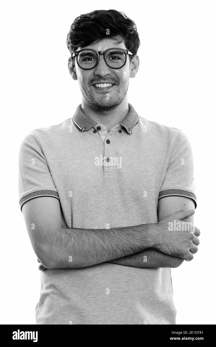 Studio shot of young happy Persian man smiling while wearing eyeglasses ...