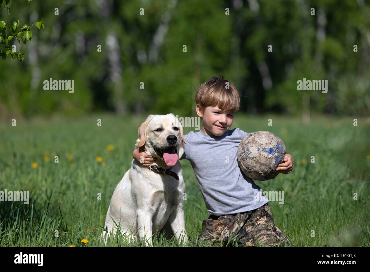 boy hugs large dog with one hand and holds soccer ball in the other ...