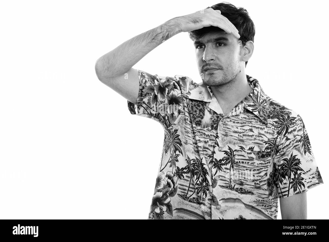 Thoughtful young Persian man using his hand as shade while looking at ...