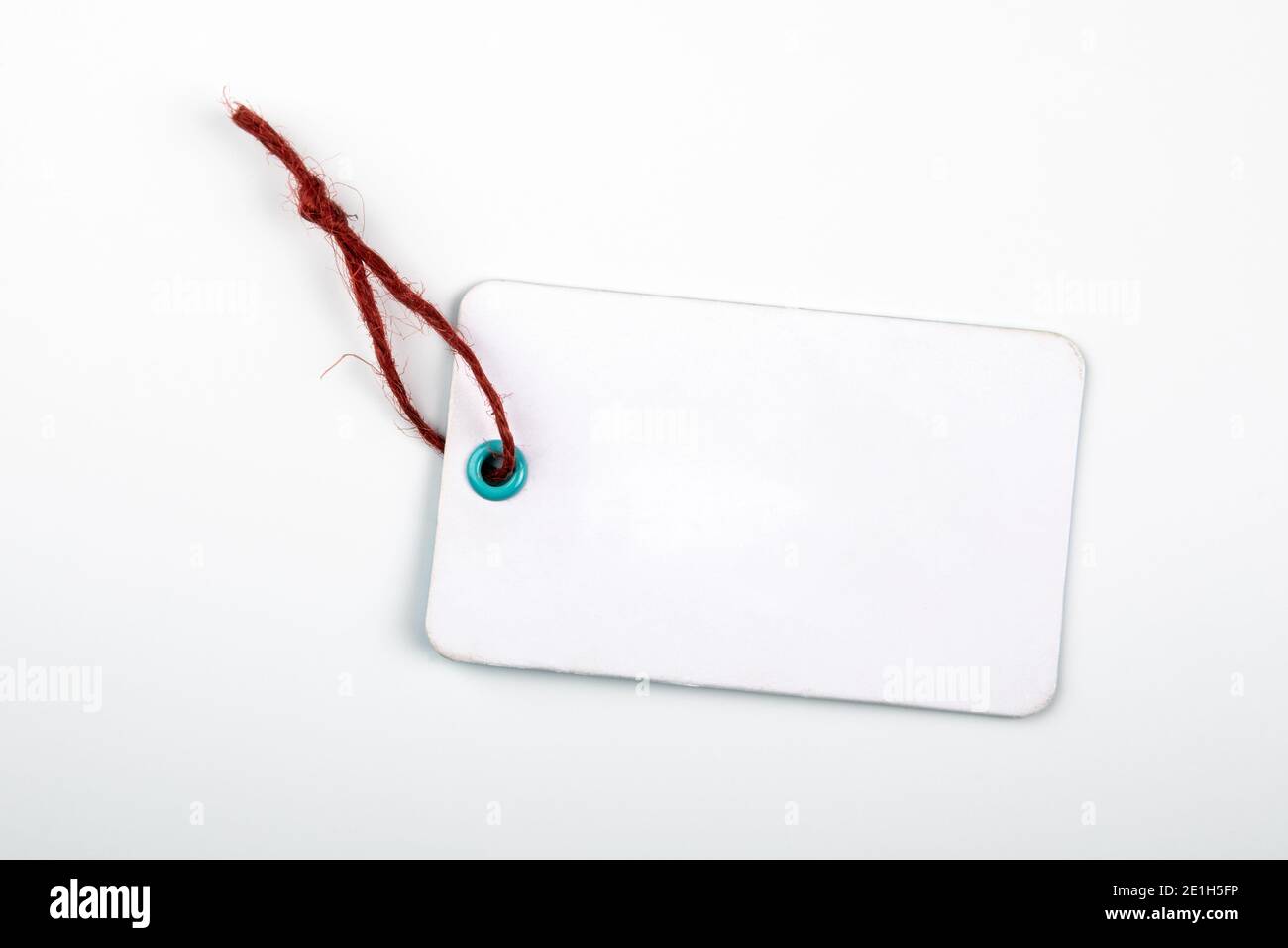 White price tag with red cord on a white background Stock Photo - Alamy