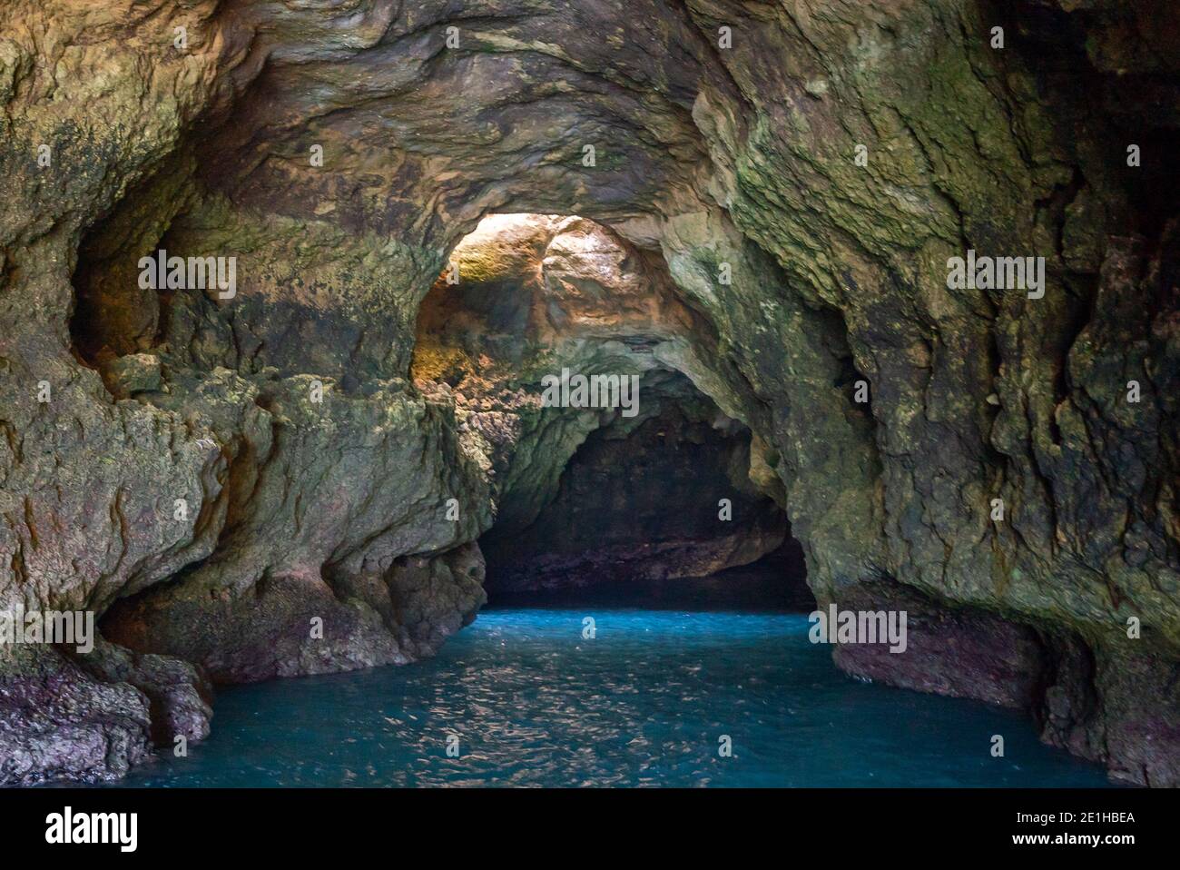 A view from inside a cave on the ocean coast with turquoise water and ...