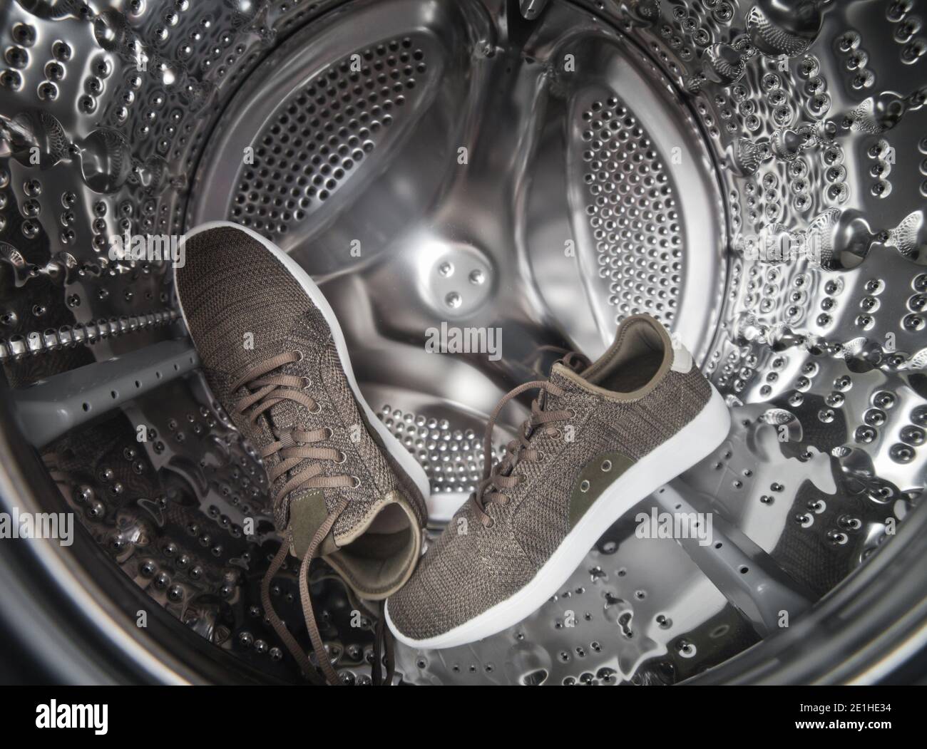Sports sneakers in metal drum of washing machine close-up. Wide angle ...