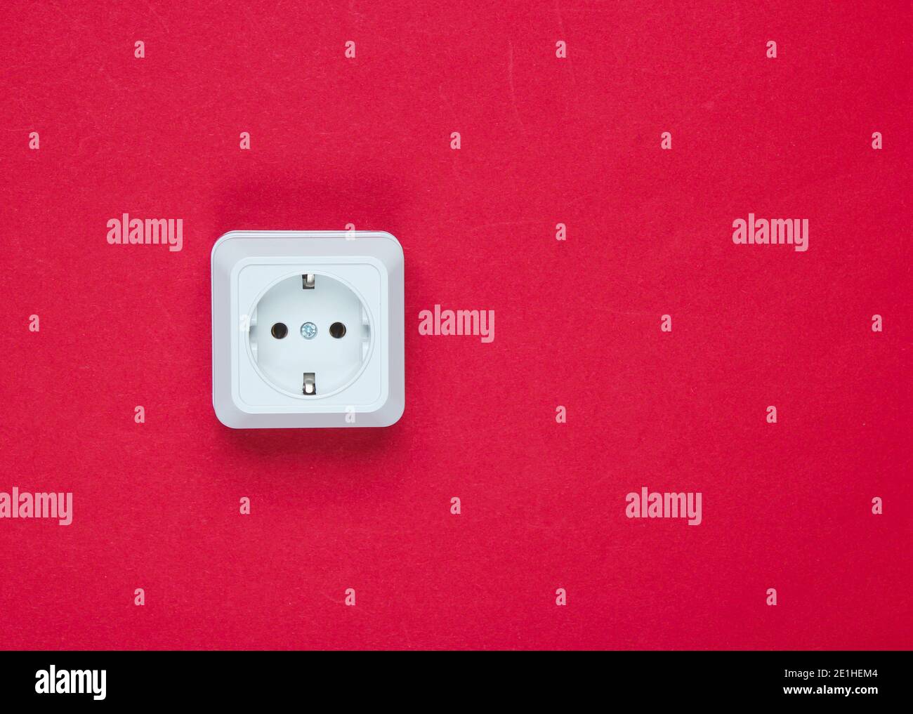 White plastic power socket on red background. Wall with copy space ...