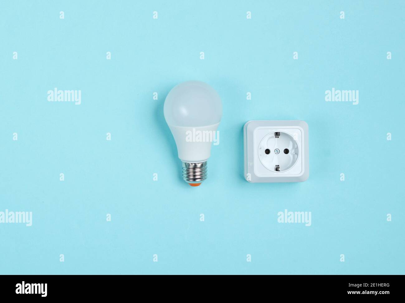 White plastic power socket and LED light bulb on blue background ...