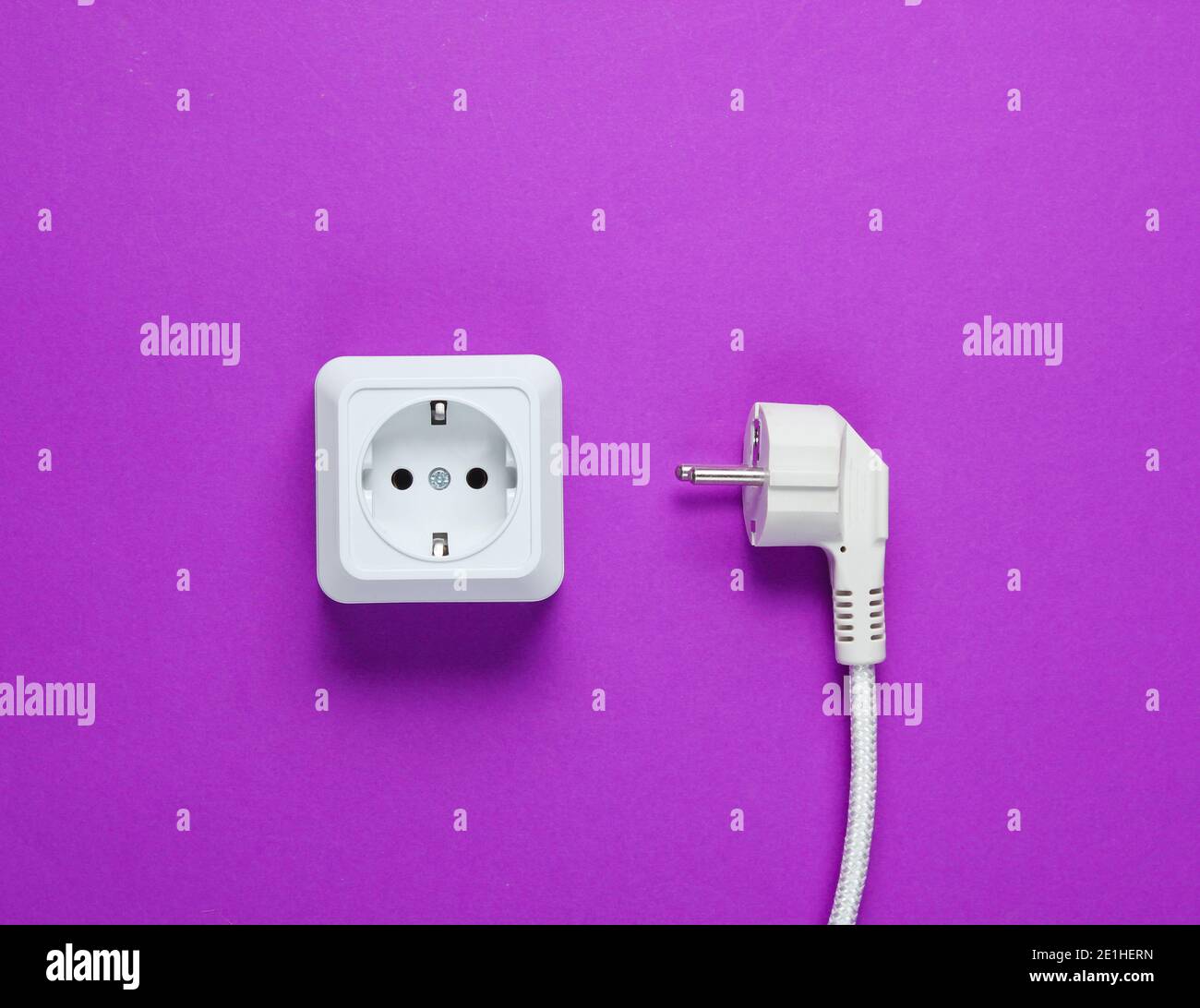 White plastic power socket and power plug on purple background. Top ...