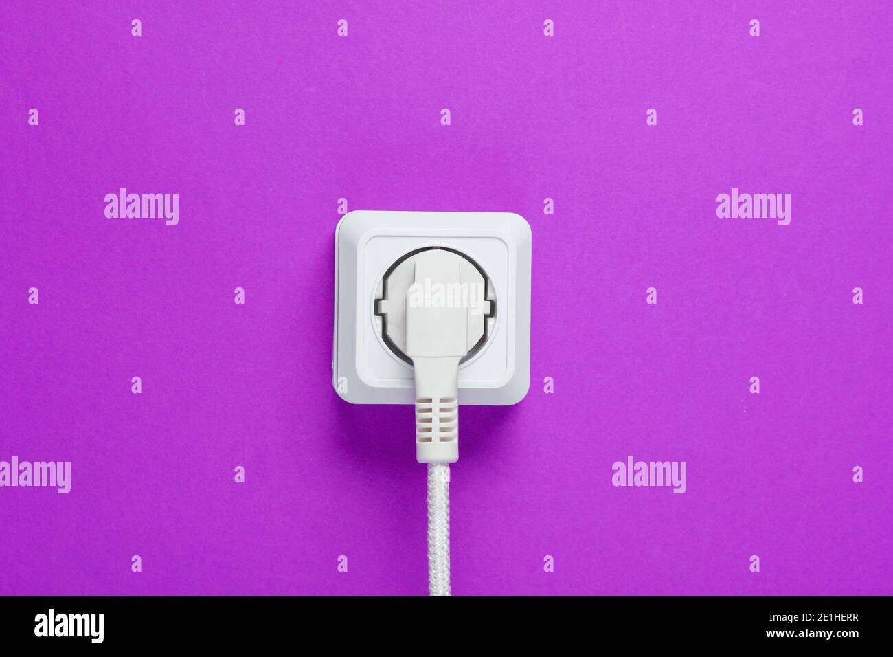 White cable plugged into power outlet on a purple wall background Stock ...