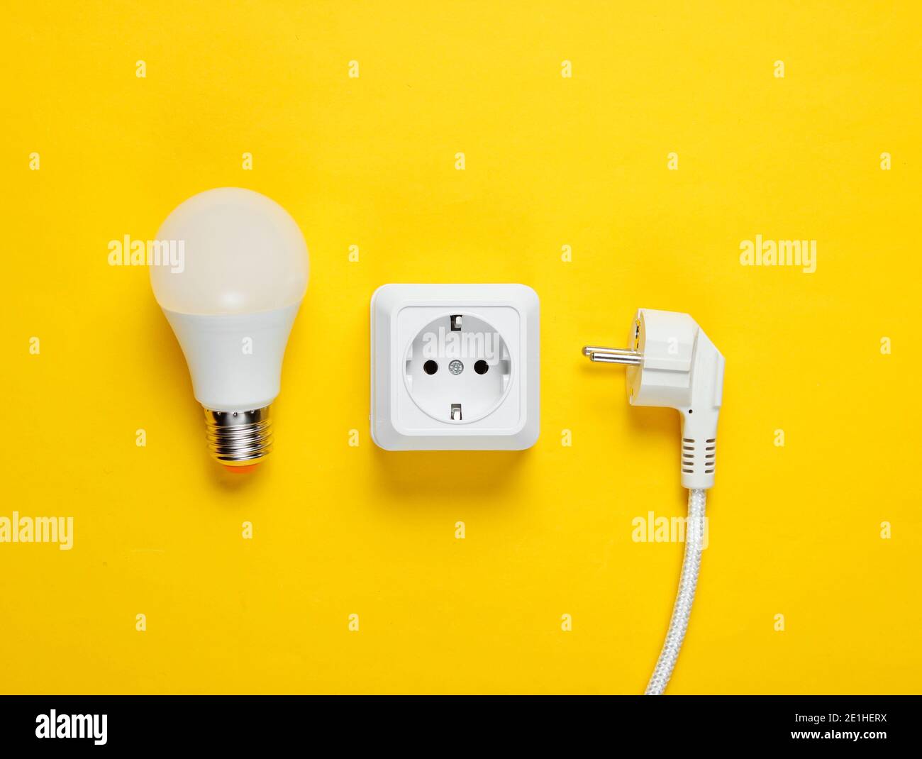 White plastic power socket, power plug, LED light bulb on yellow ...