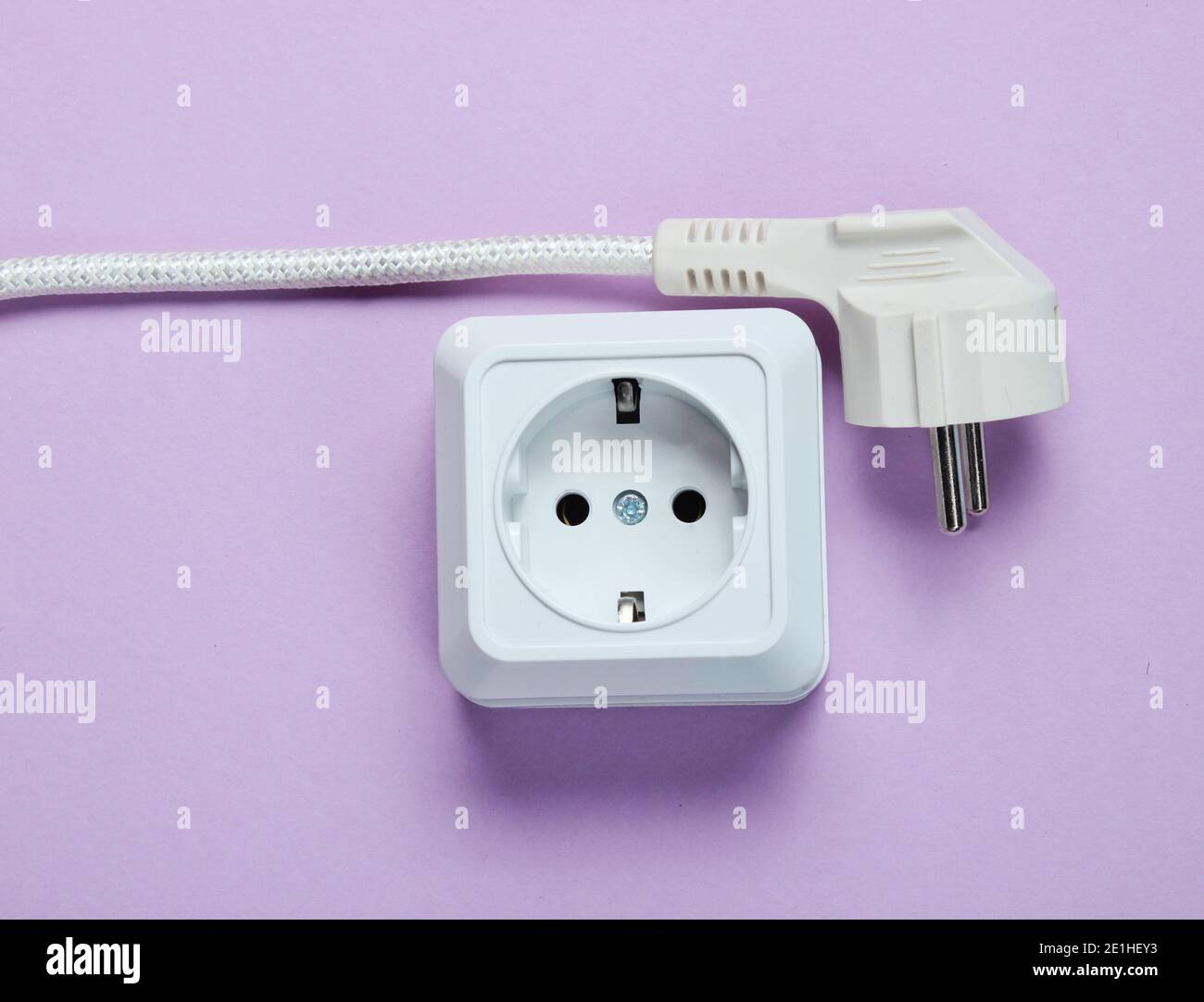 White plastic power socket and power plug on purple background. Top ...
