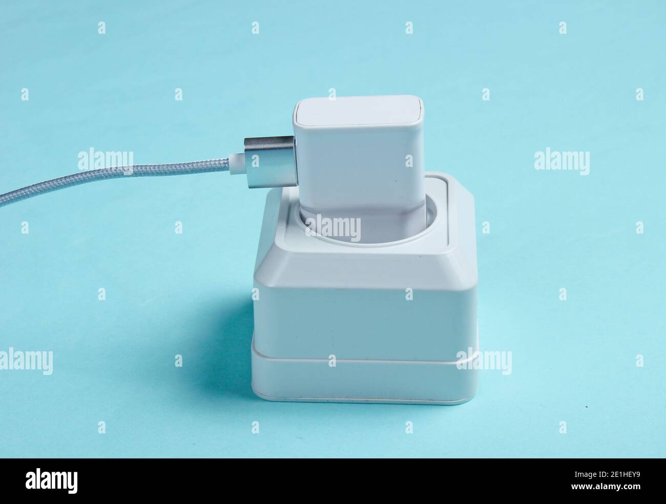 Charger plugged into power outlet on blue background Stock Photo - Alamy