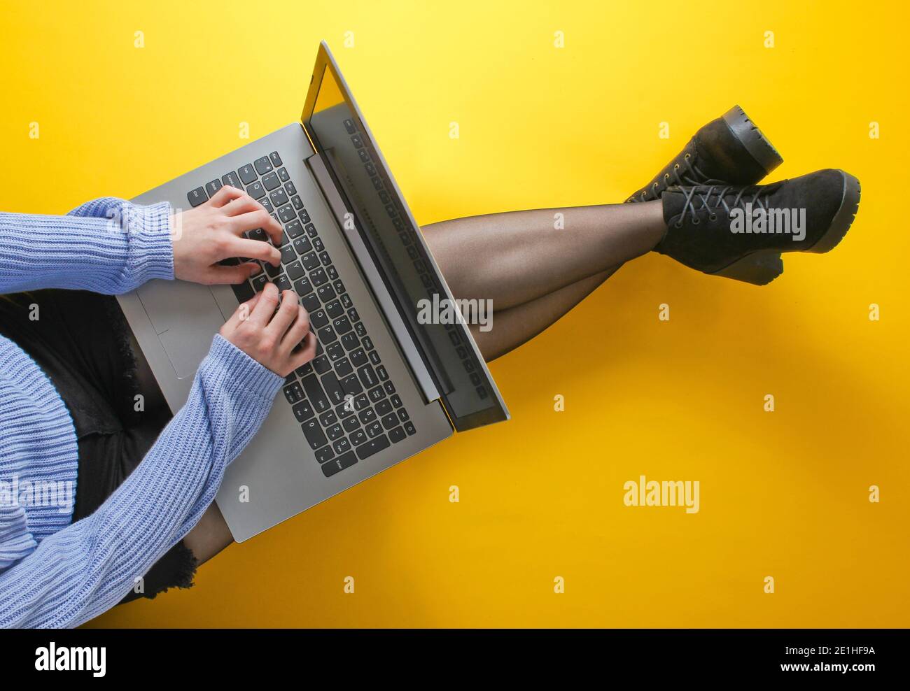 Business woman in shorts, tights and boots is typing on a laptop while ...