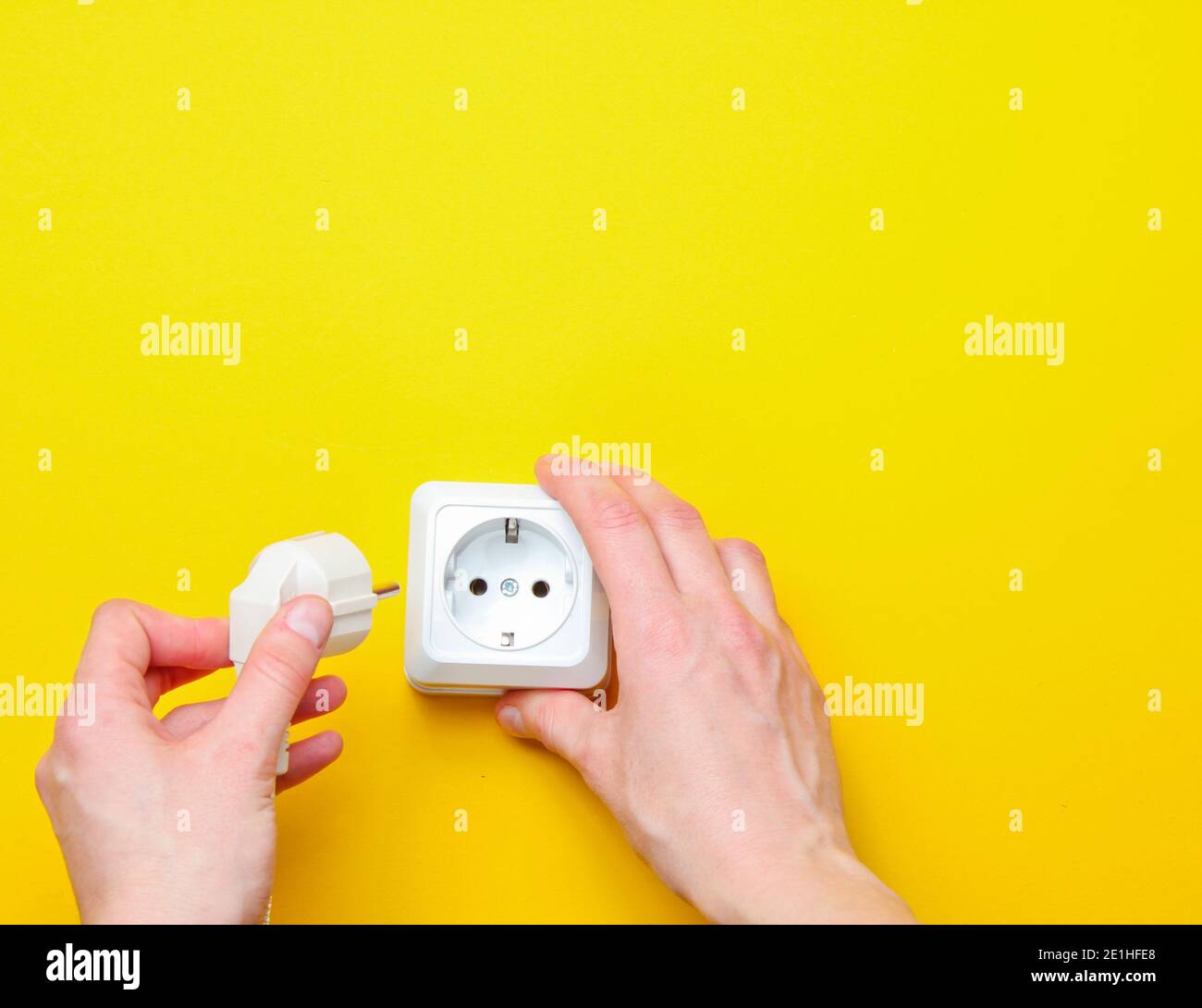 Female hands plug in power plug into electro outlet on yellow ...