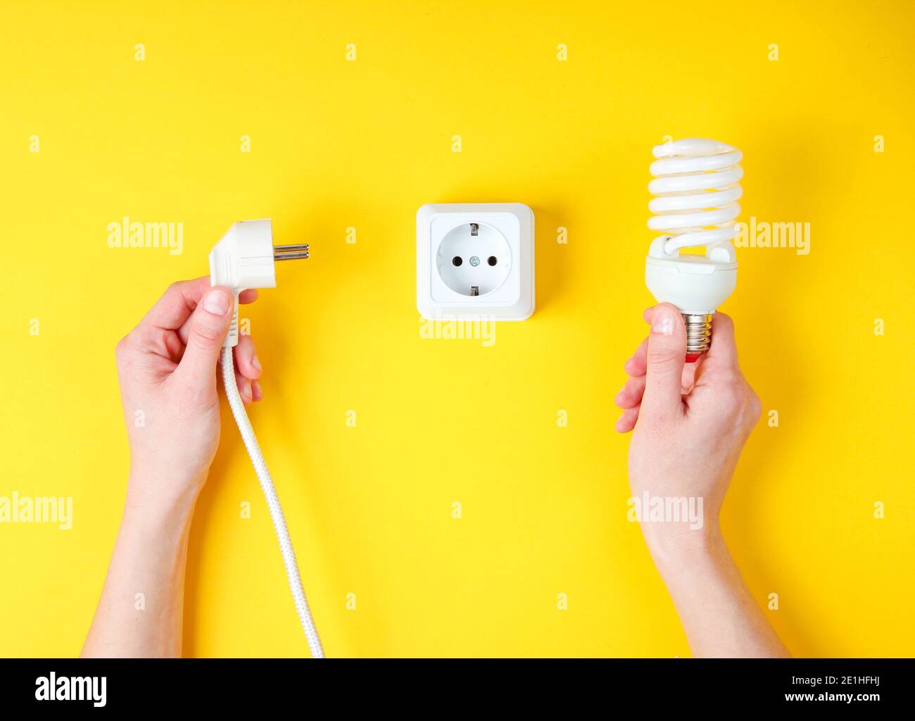 Female hands plug the power plug into electrical outlet while holding ...
