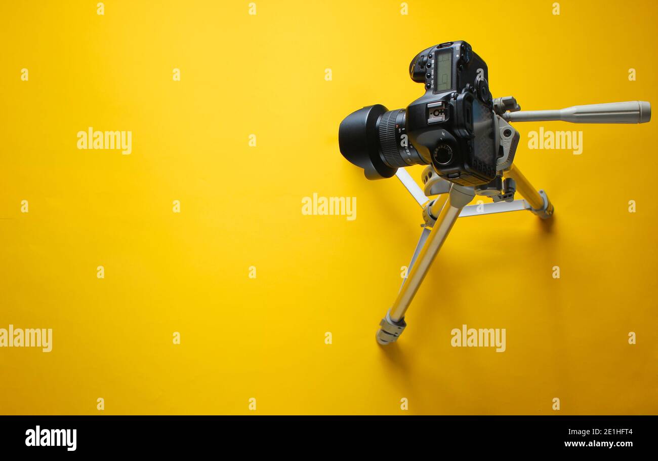 Modern digital camera with tripod on yellow background. Minimalism. Top ...