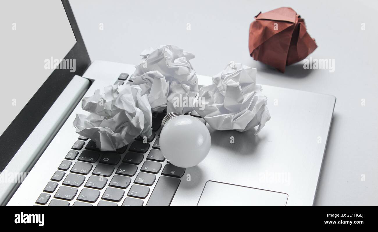 Idea business concept. Laptop, crumpled paper balls, LED light bulb on ...