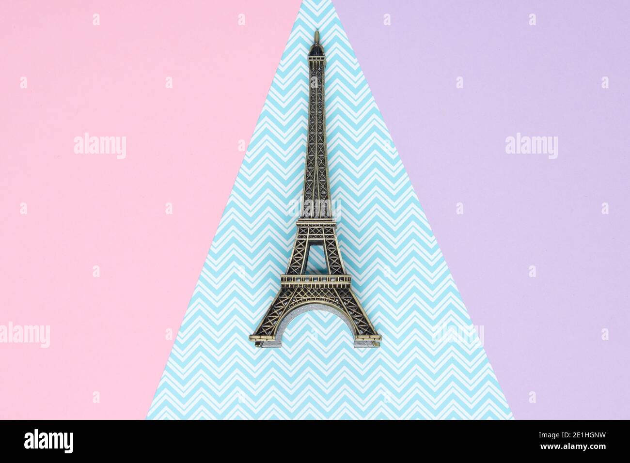 Mini statuette of the Eiffel Tower on a pastel paper background. Top ...