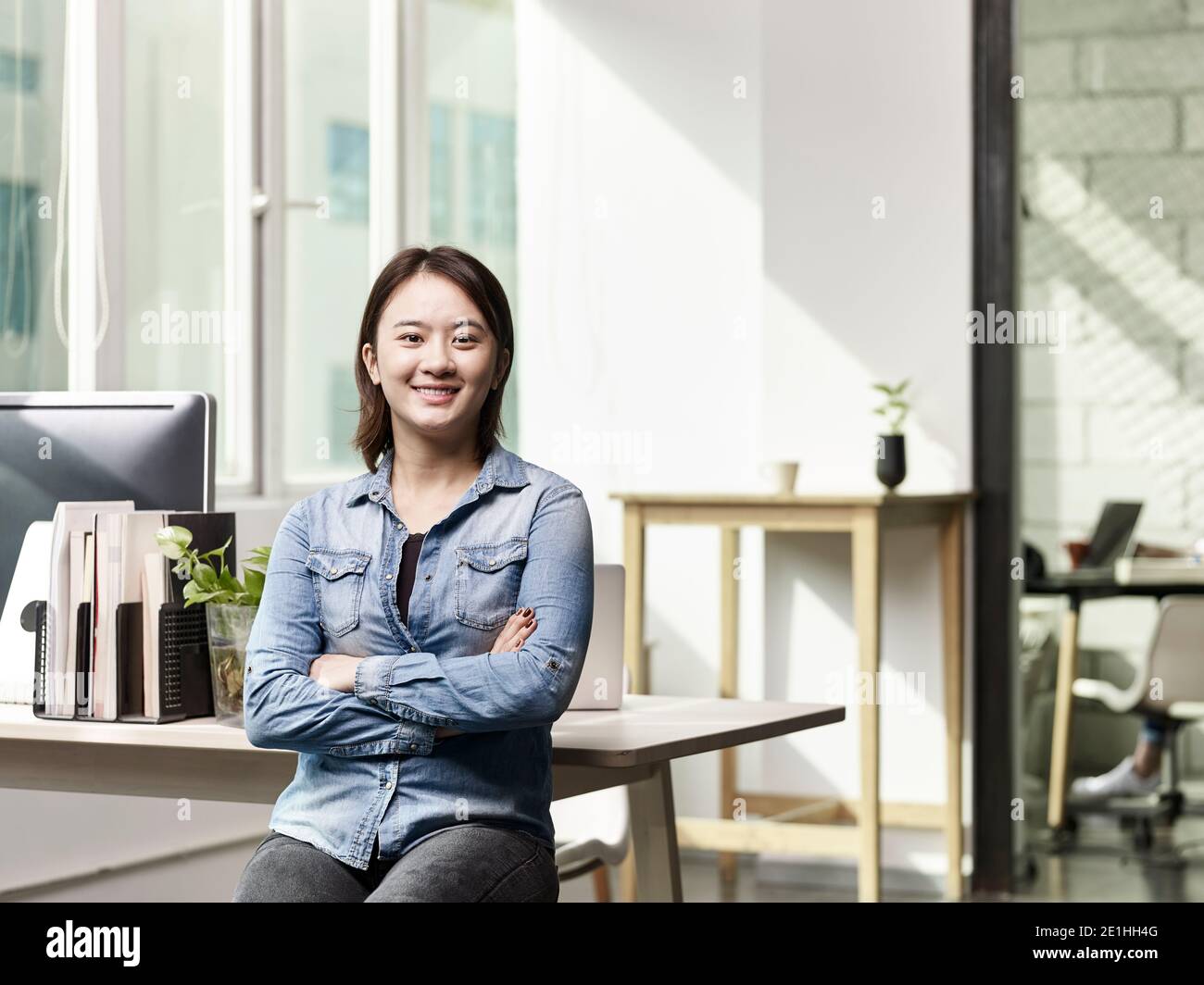 portrait of a young asian business woman looking at camera smiling arms ...