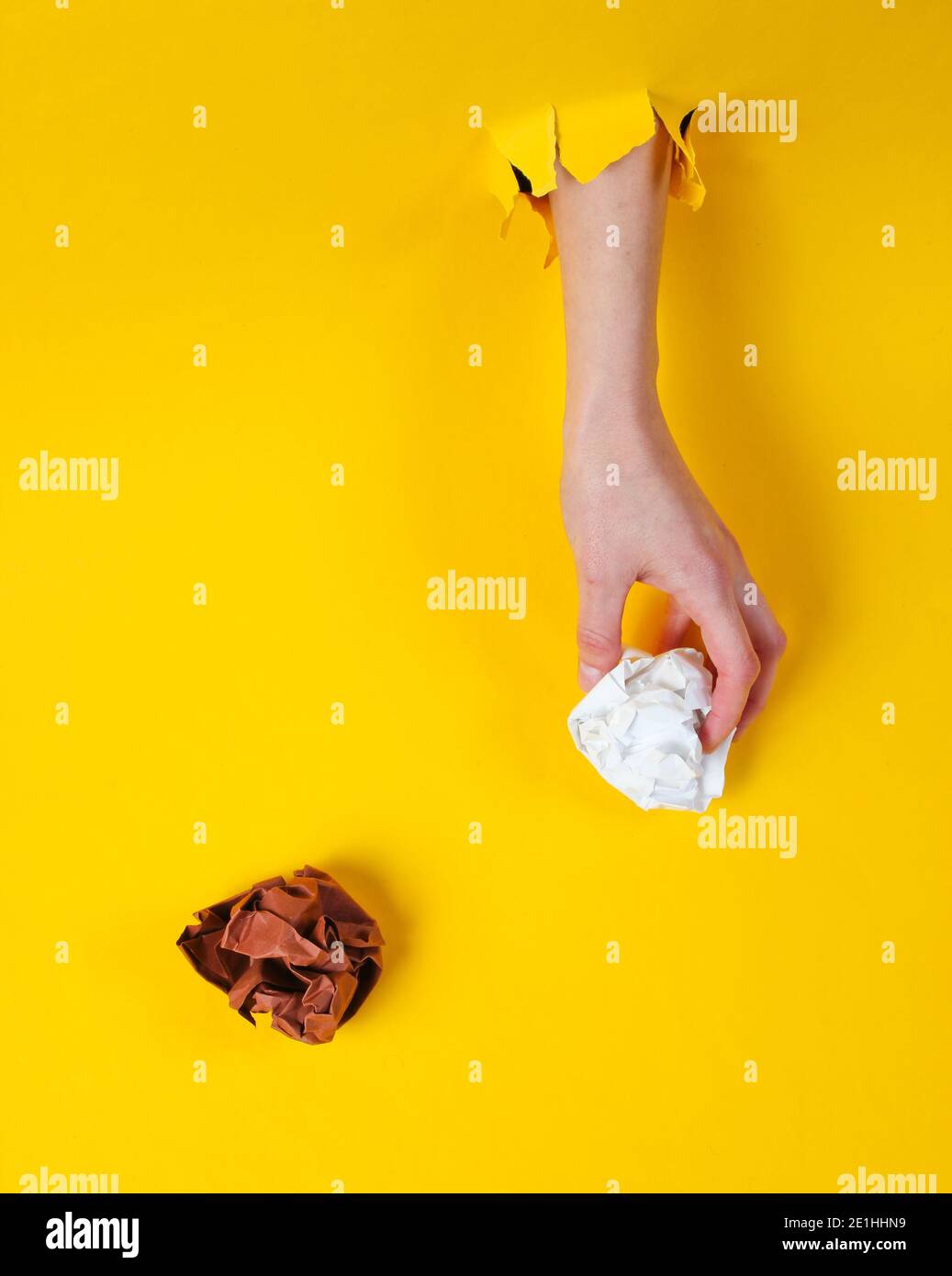 Female hand holds crumpled balls of paper through torn yellow paper ...