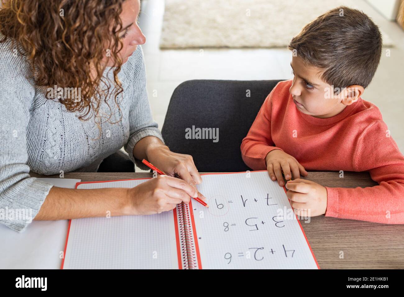 Sad child for having made a mistake doing homework with his mother ...