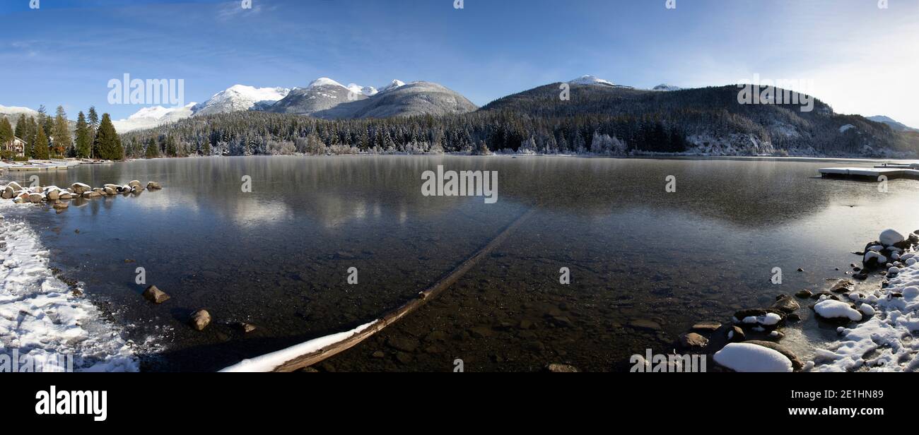 Stunning winter landscape panorama. Frozen lake and snow capped ...