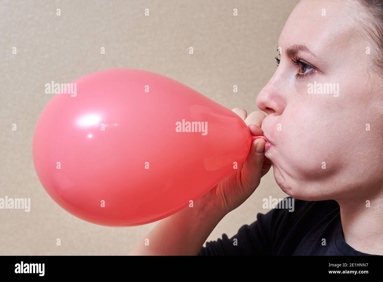 Young woman inflate a red balloon, the theme of holidays and parties ...