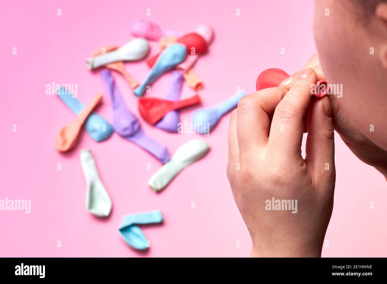 Woman starts to inflate a balloon on a pink background Stock Photo - Alamy