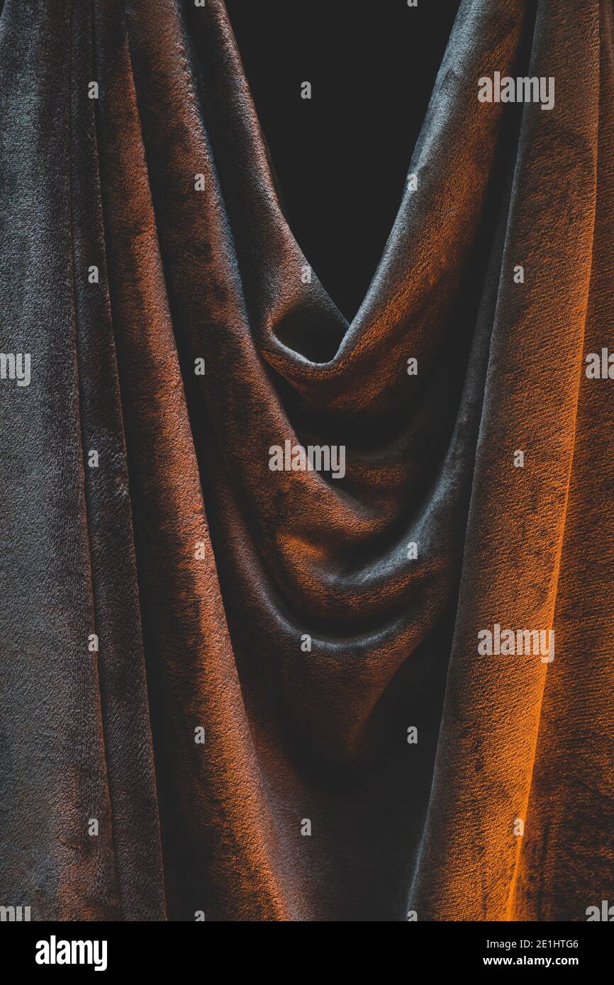 Detail of draped and crumpled velvet fabric, moody warm lighting ...