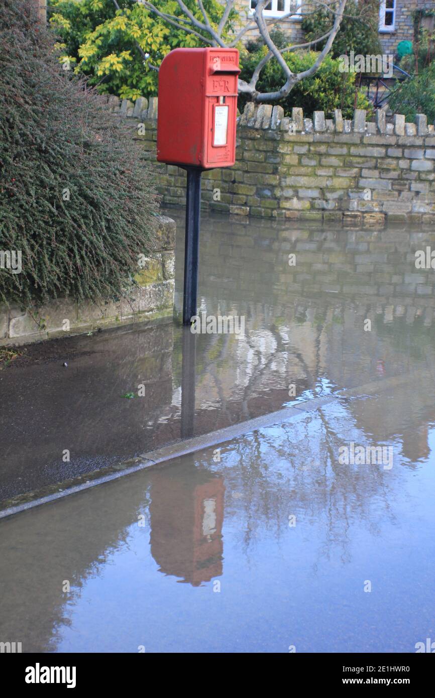 Roads in a village in Somerset flooded. A post box rising above the ...