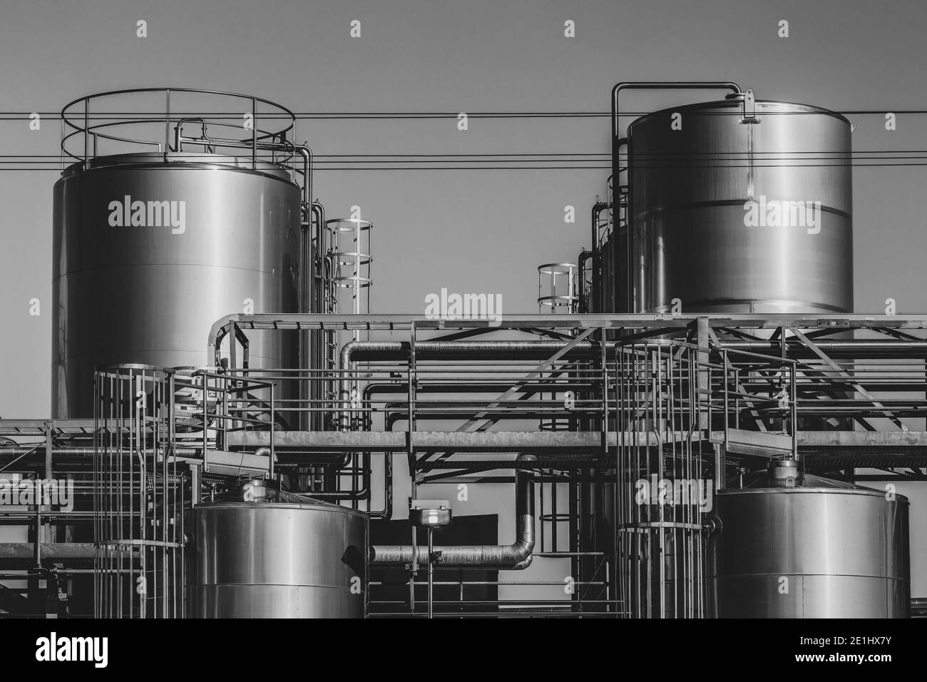 Giant metal storage tanks linked by pipes and a catwalk. Photographed ...