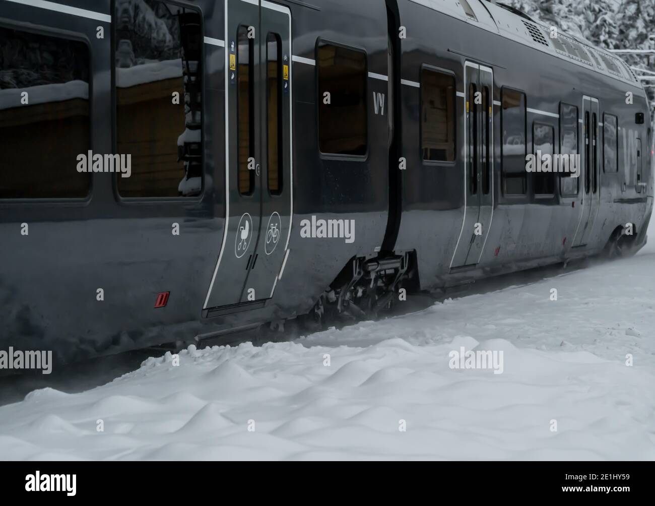 Passenger train from Oslo passing by a station on a cold, snowy winters ...