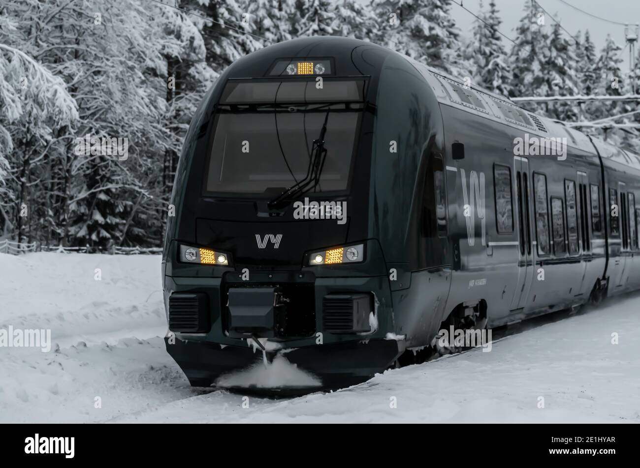 Passenger train from Oslo passing by a station on a cold, snowy winters ...