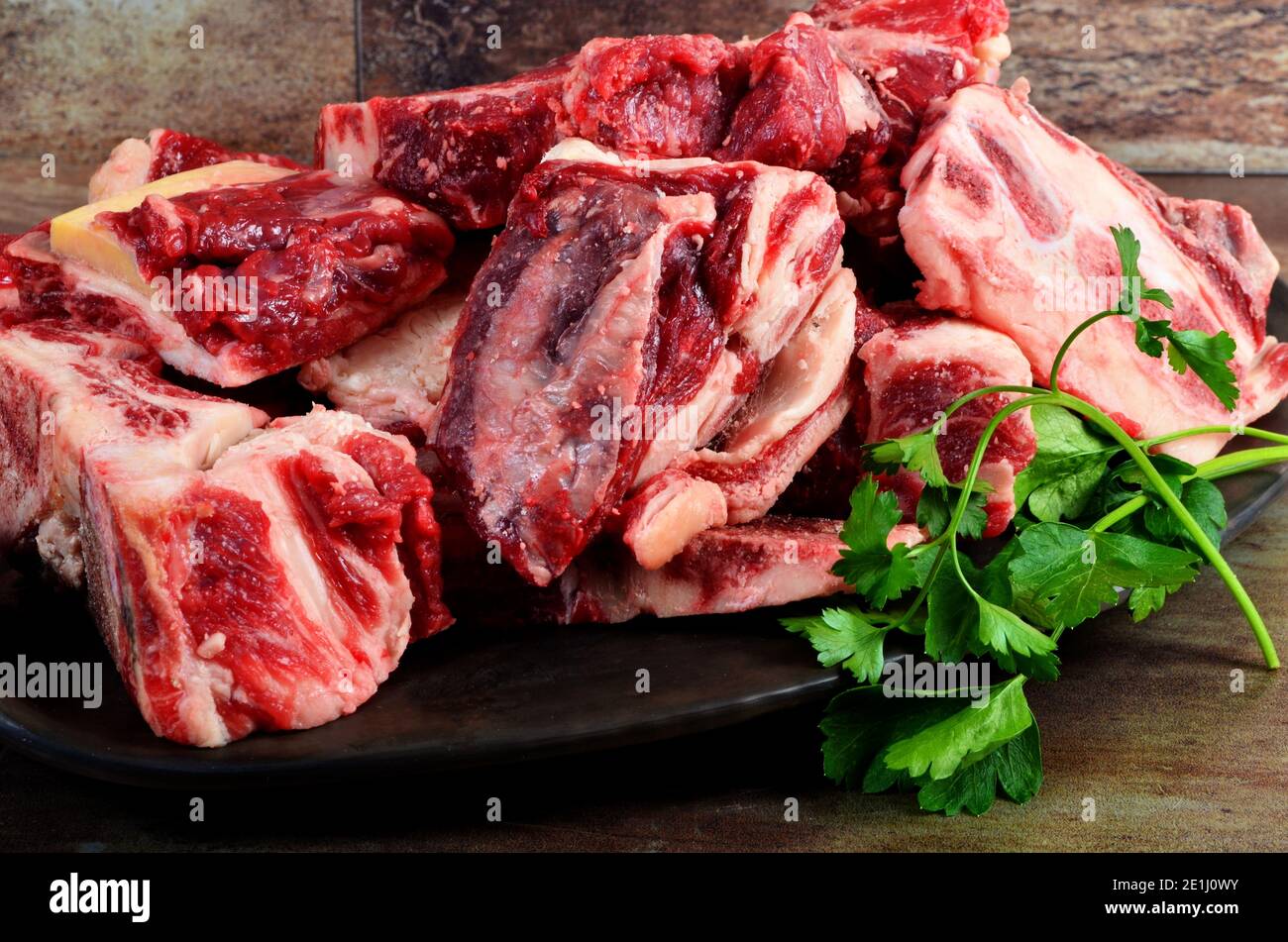 Raw meat with bone on clay plate and brown stone background.Raw meat ...
