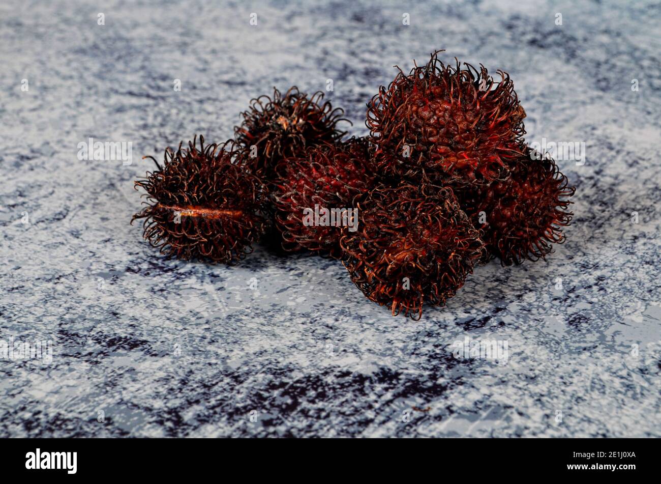 Very ripe rambutan fruit on a blue stone background Stock Photo - Alamy
