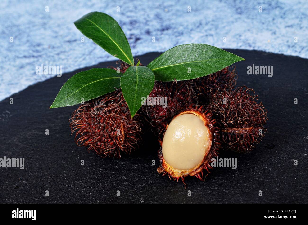 Very ripe rambutan fruit on a blue stone background Stock Photo - Alamy