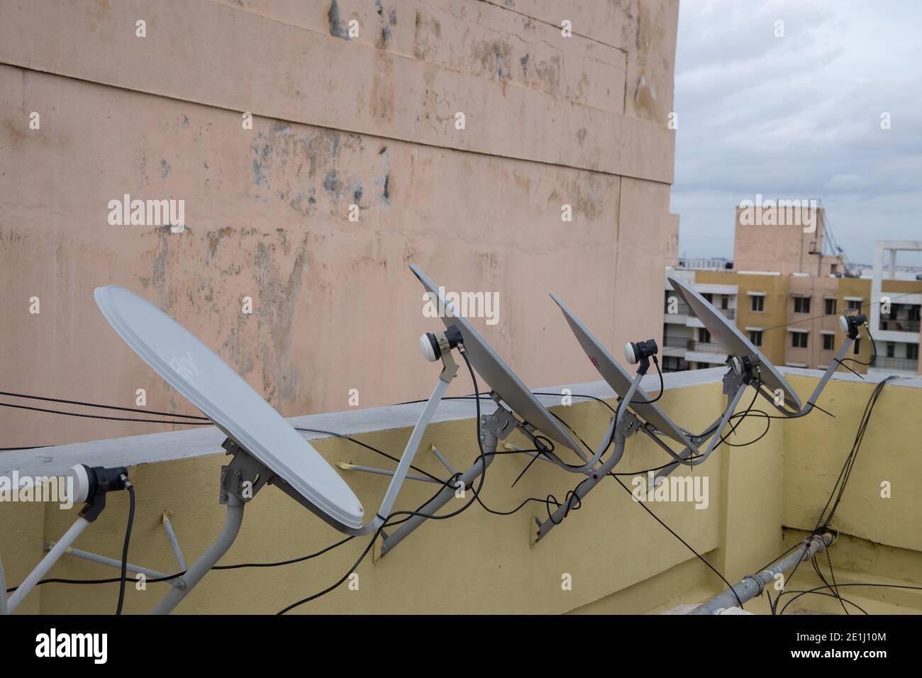 A row of dish antennas fixed on the wall of the roof top and pointing ...