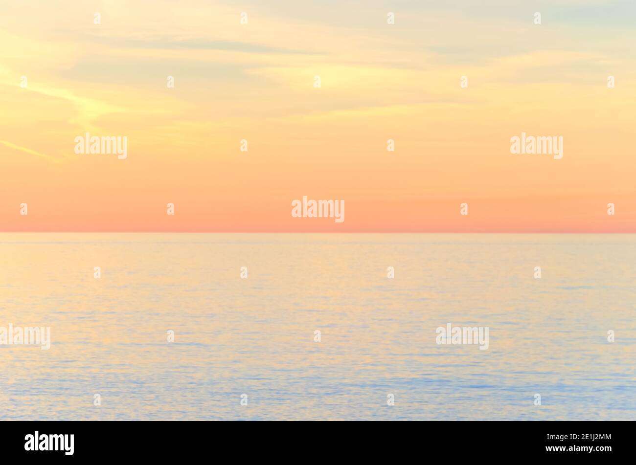 Unfocused blurred sunset over the sea in pastel colors. Natural warm ...
