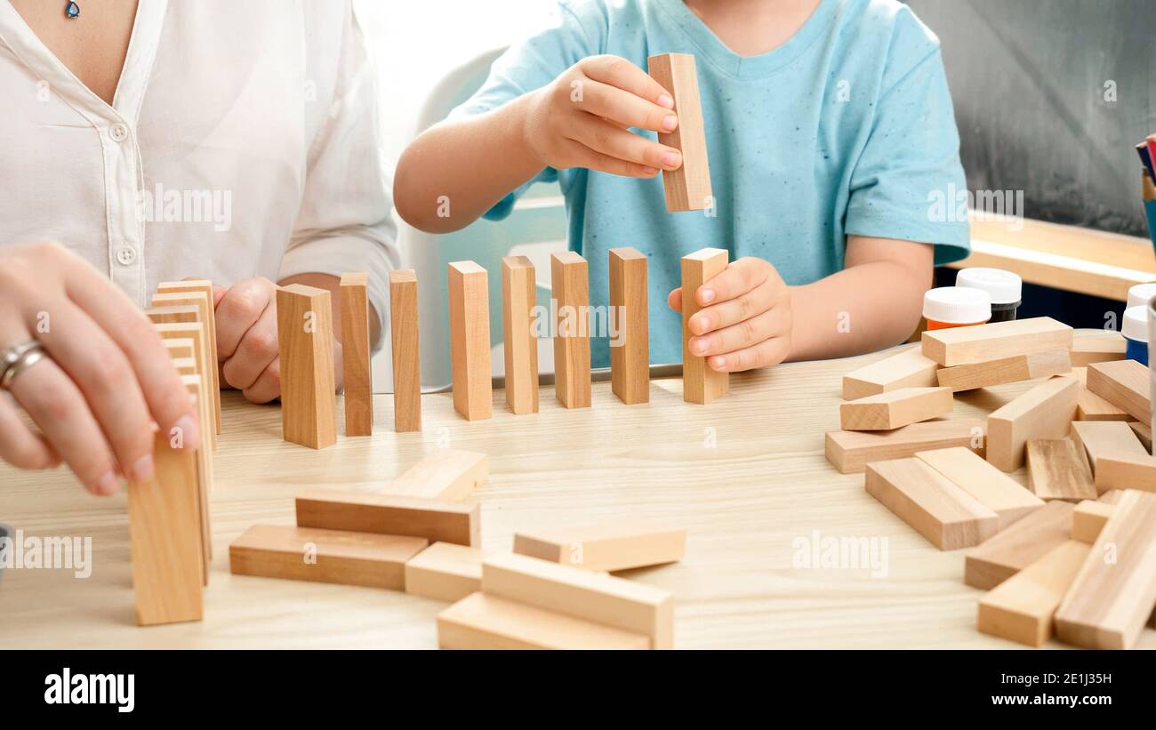 Boy pushing wooden block and starting domino effect. Wooden blocks ...