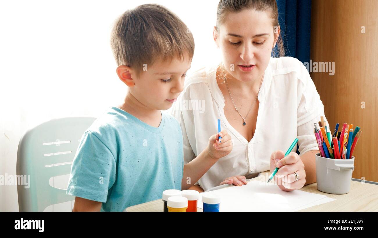 Little boy sitting behind desk at school classroom and learning drawing ...