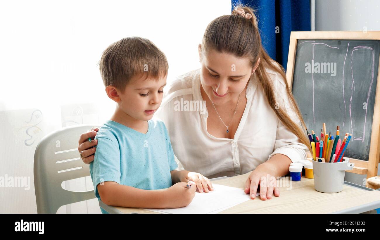 Teacher teaching drawing her little toddler son with colorful pencils ...