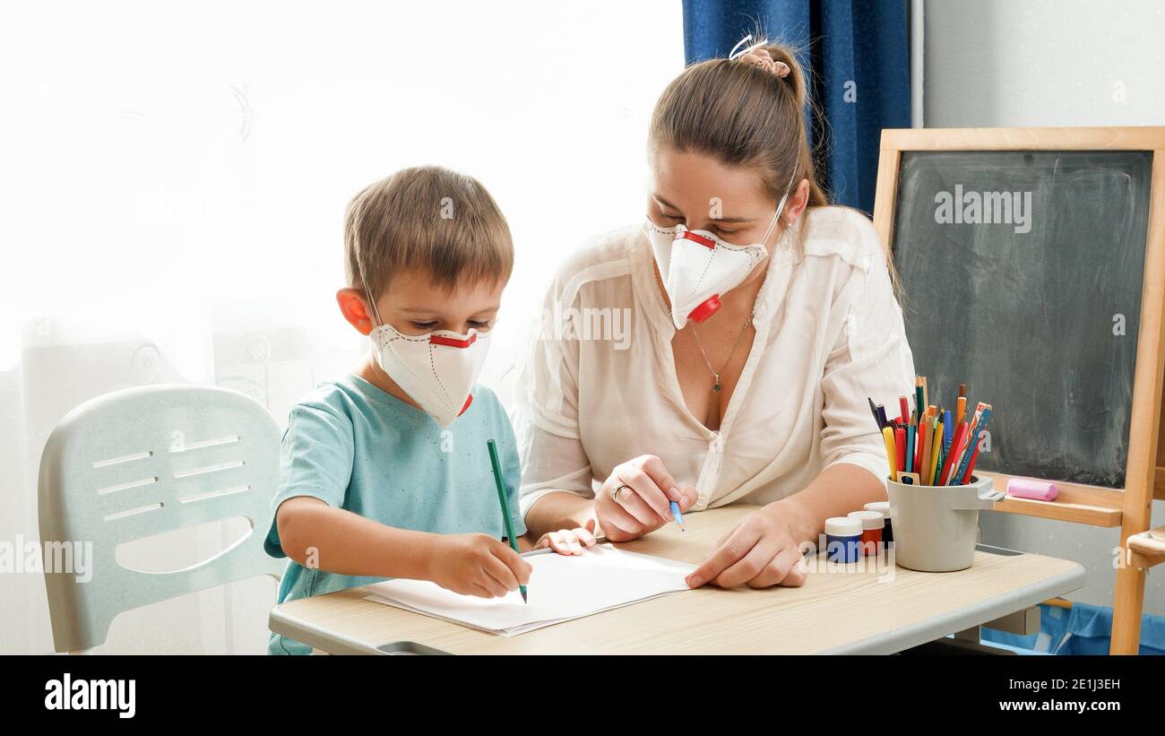 Young female teacher and little boy wearing protective mask respirators ...
