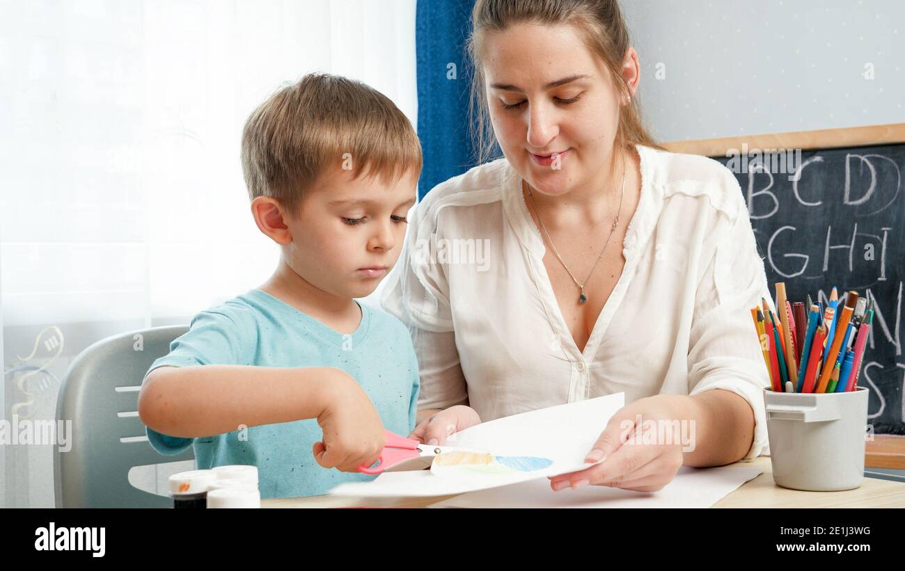 Young female teacher showing her little student how to use scissors ...