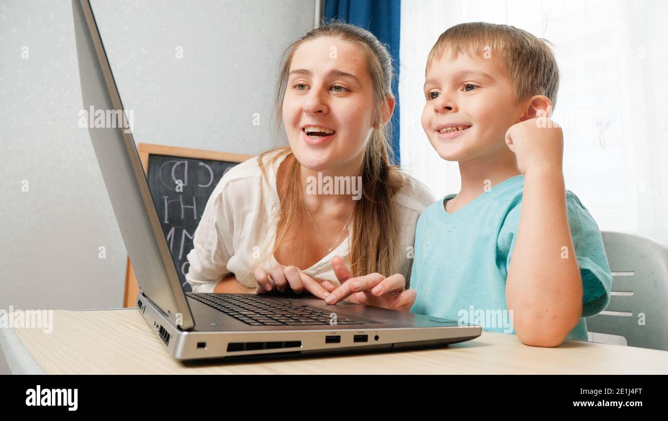 Happy smiling mother with little son using laptop and looking on ...