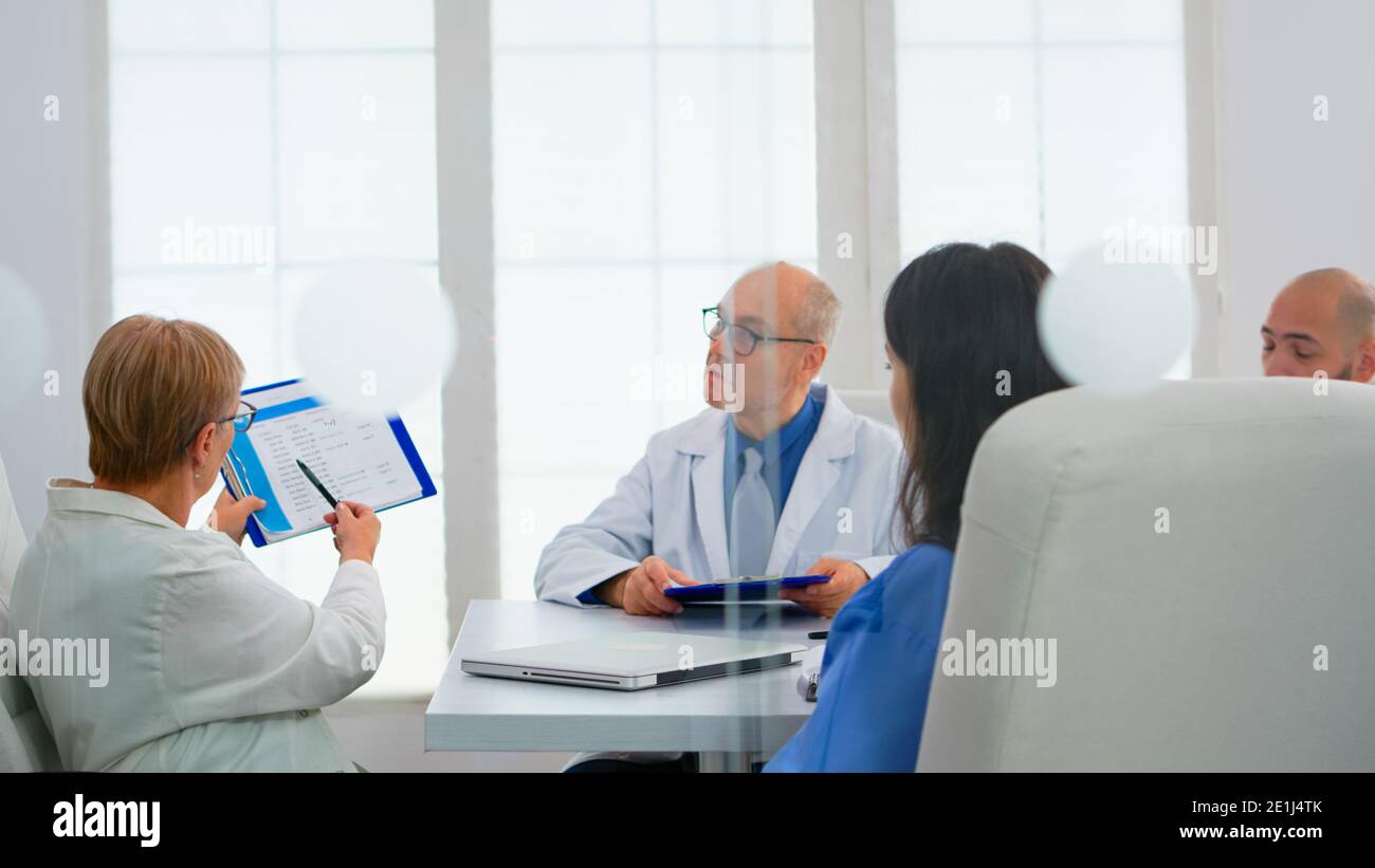 Elderly doctor having medical conference in hospital meeting room ...