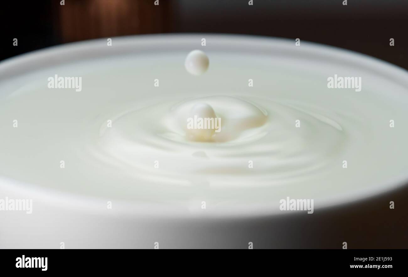Milk drop falls into the filled cup Stock Photo - Alamy